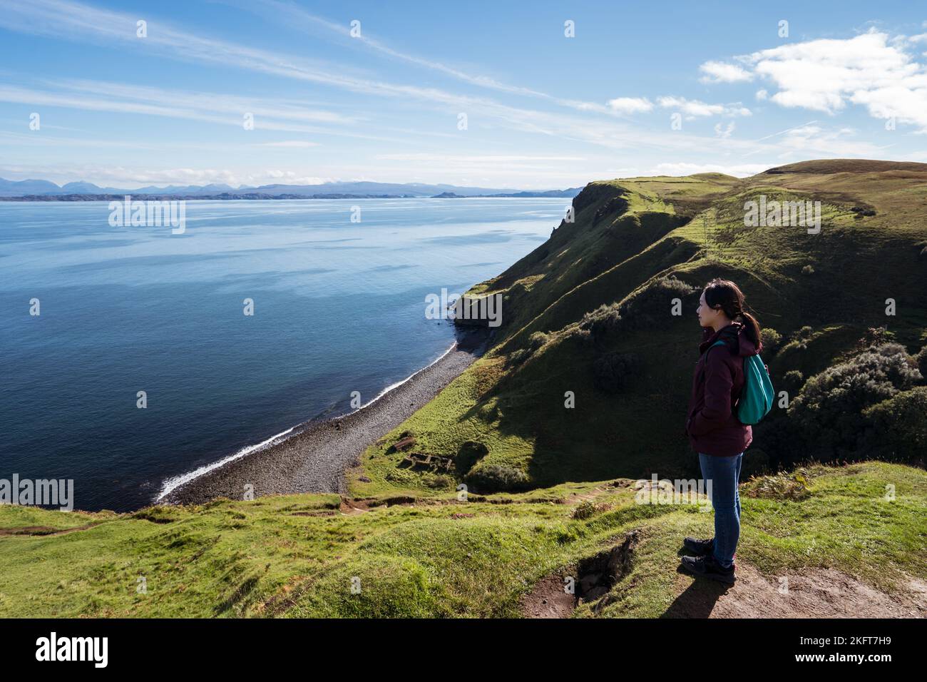 Side view of young ethnic female in warm clothes standing on green ...