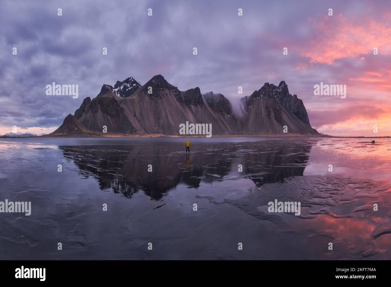 Silhouette of anonymous tourist standing on wet shore near calm sea and ...