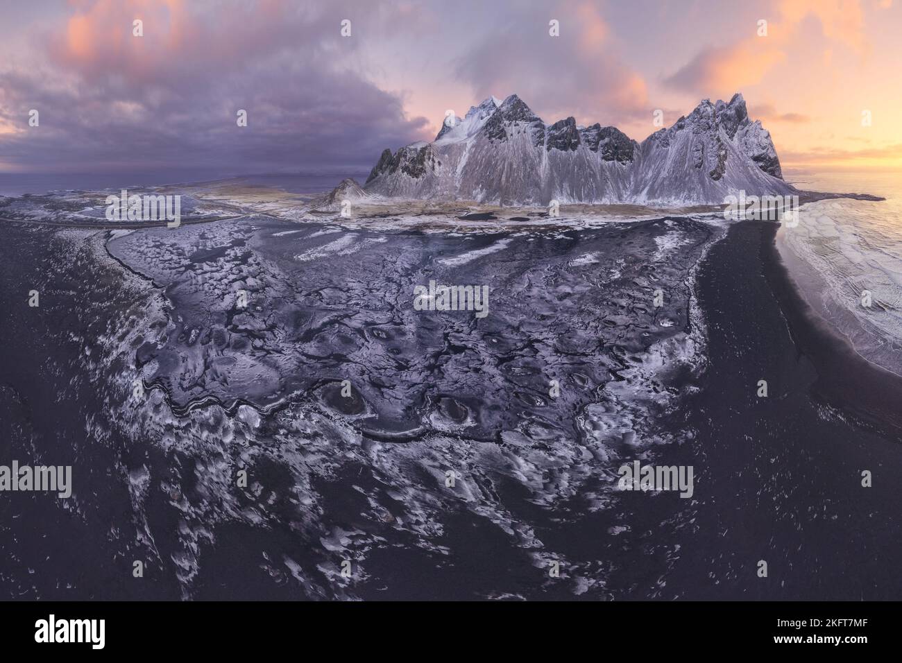 Calm frozen endless sea surrounding with black frozen sand and high ...