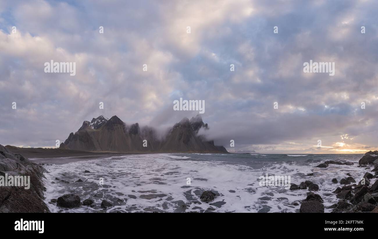 Picturesque scenery of waving sea washing rough shore near high snowy ...