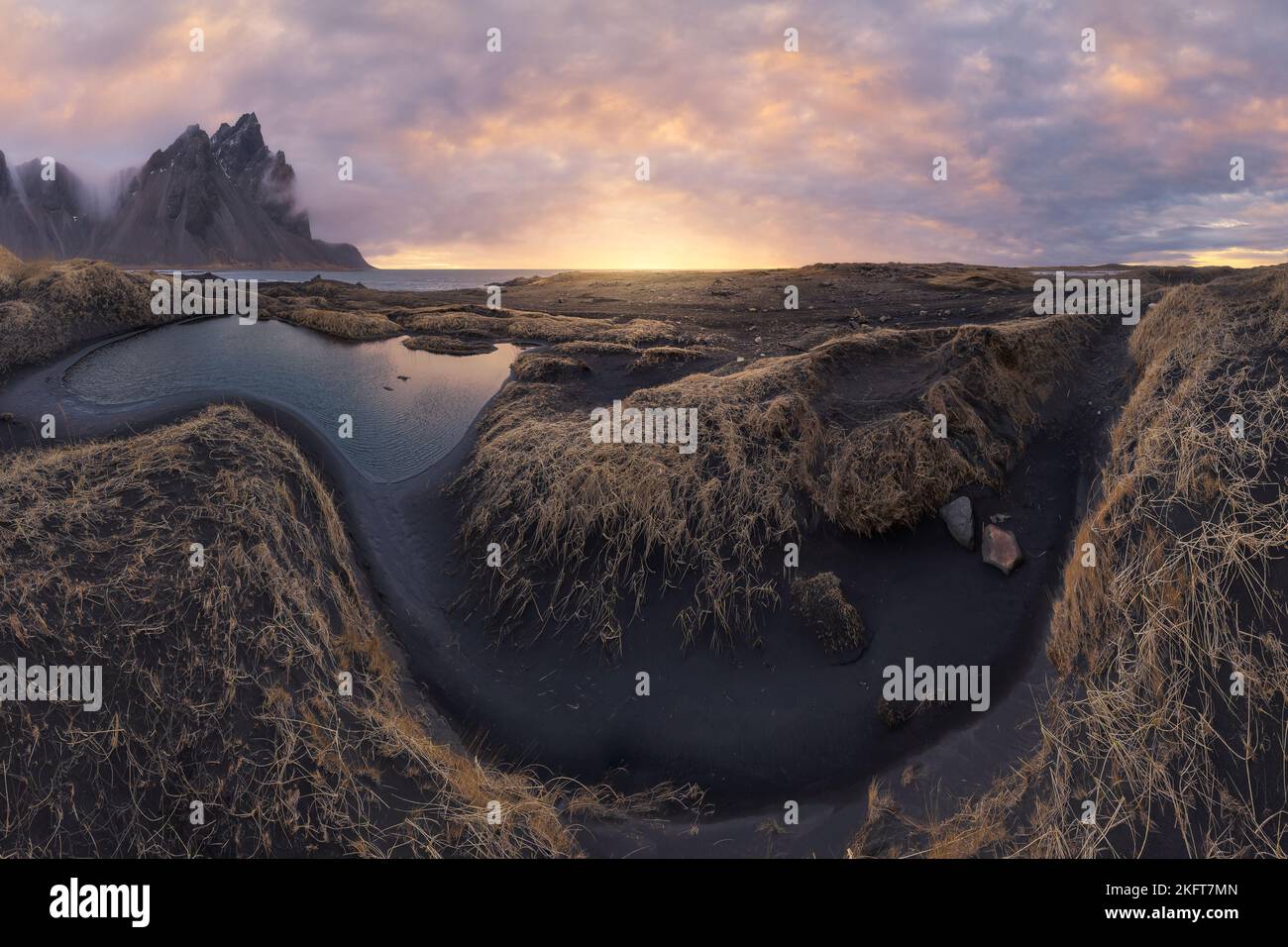 Mountain range against cloudy sky during sunset near black sand beach ...