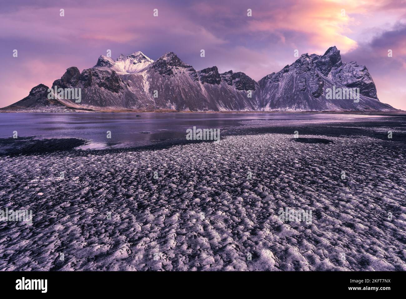 Calm frozen endless sea surrounding with black frozen sand and high ...