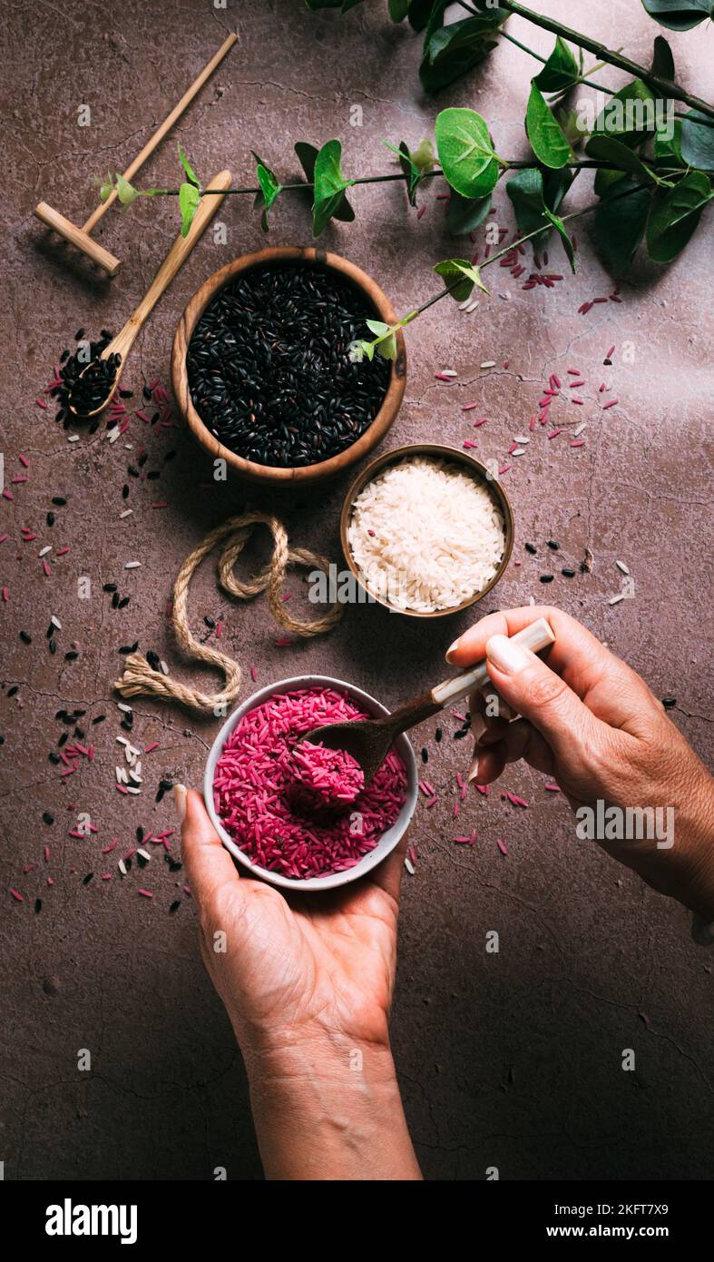Top view of female demonstrating bowls and spoon of assorted rice over ...