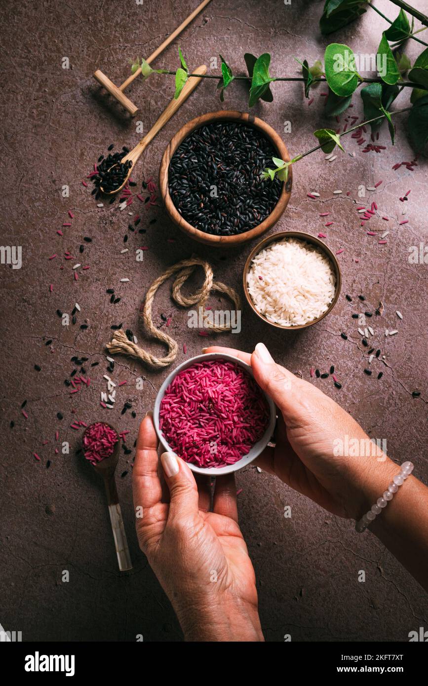 Top view of female demonstrating bowls and spoon of assorted rice over ...
