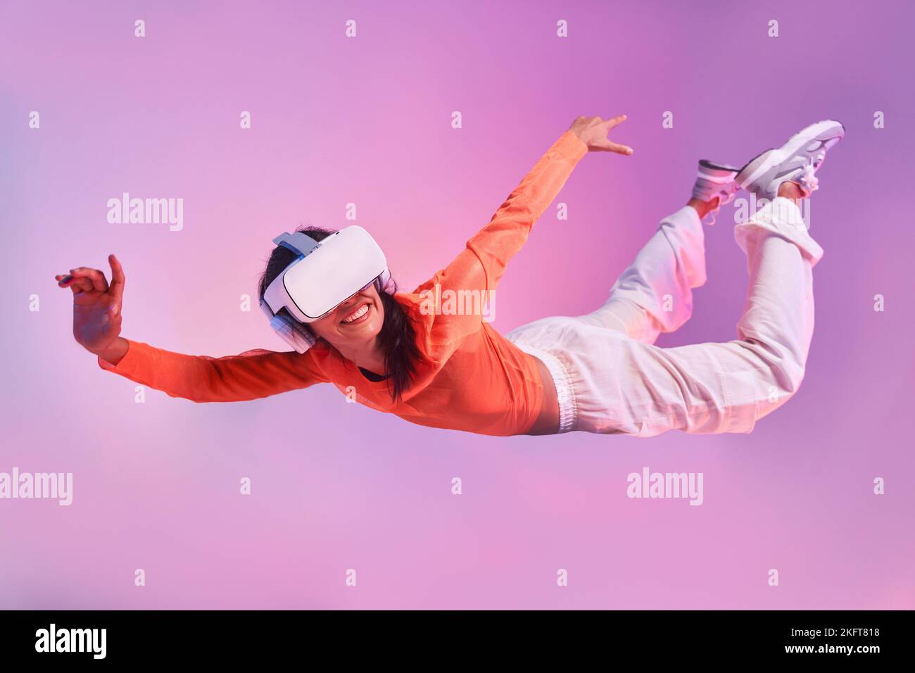 Full body female in VR helmet suspended in the air against violet ...