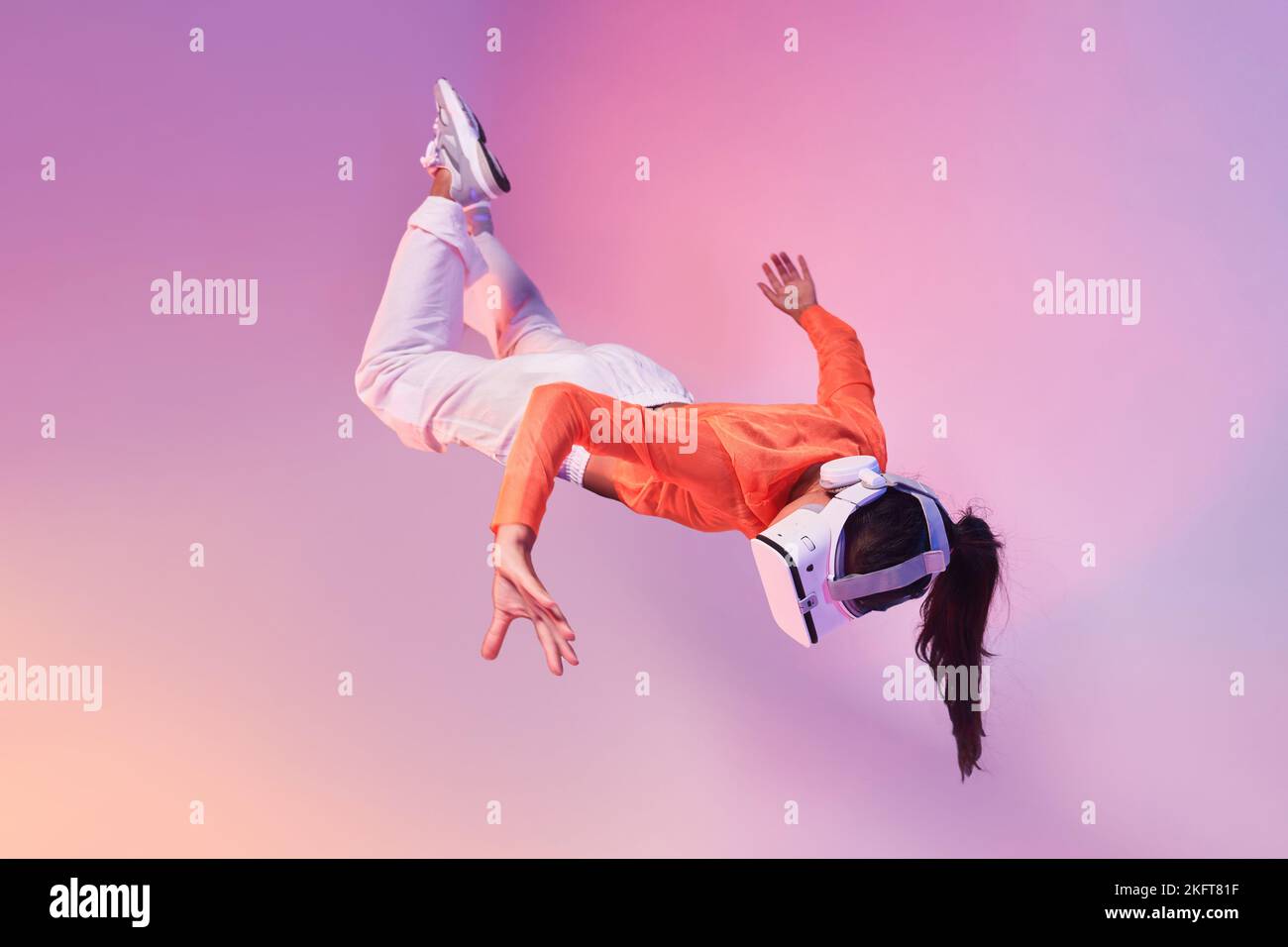 Full body female in VR helmet falling down against violet background ...
