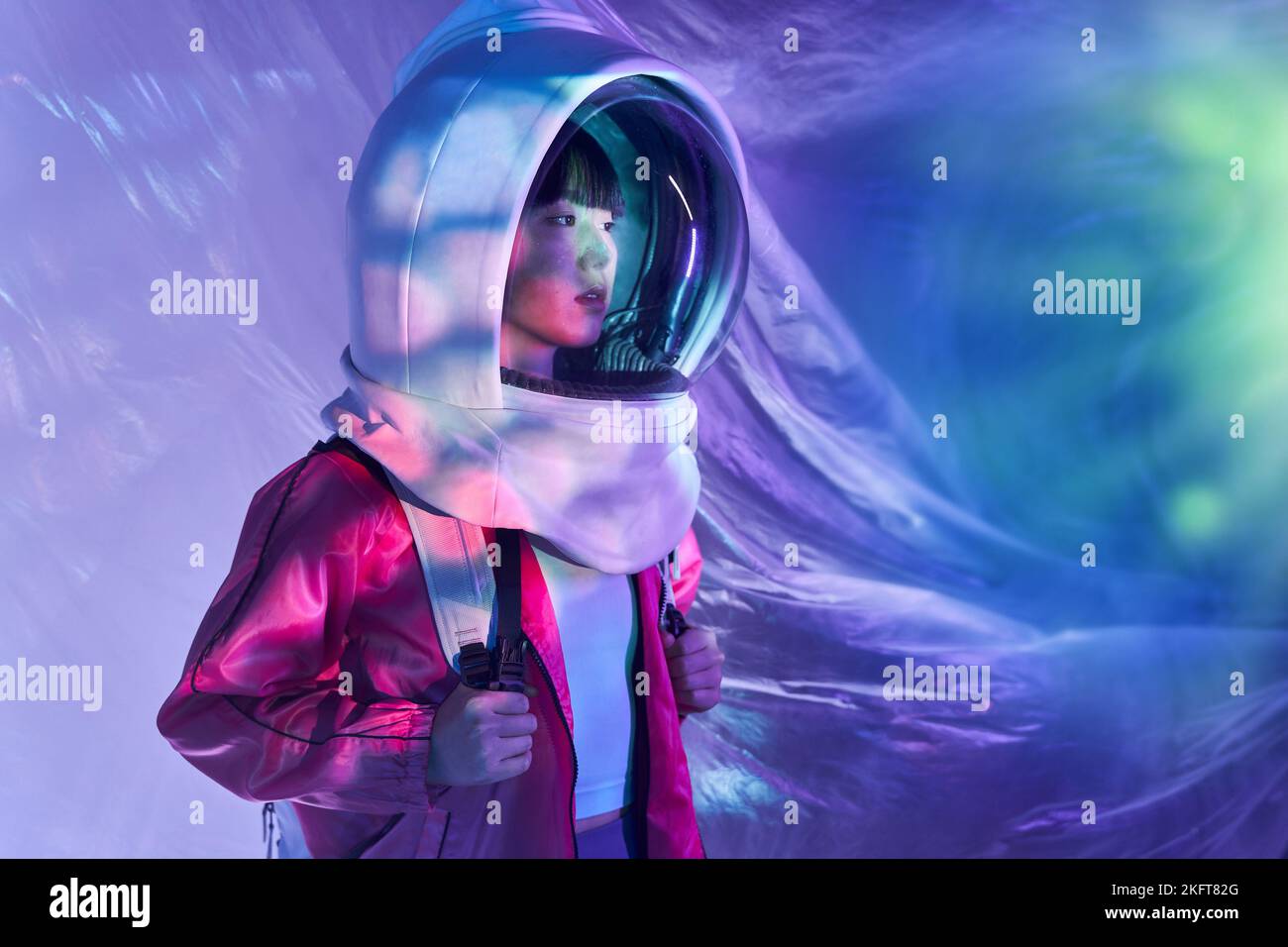 Young Asian female with backpack wearing cosmonaut helmet and closing ...