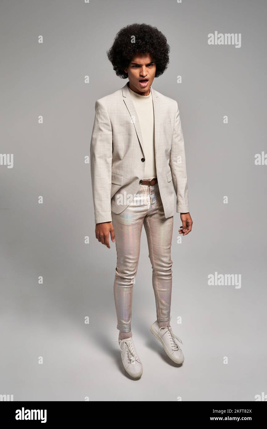 Full body Hispanic man in stylish suit with Afro hairstyle raising leg ...