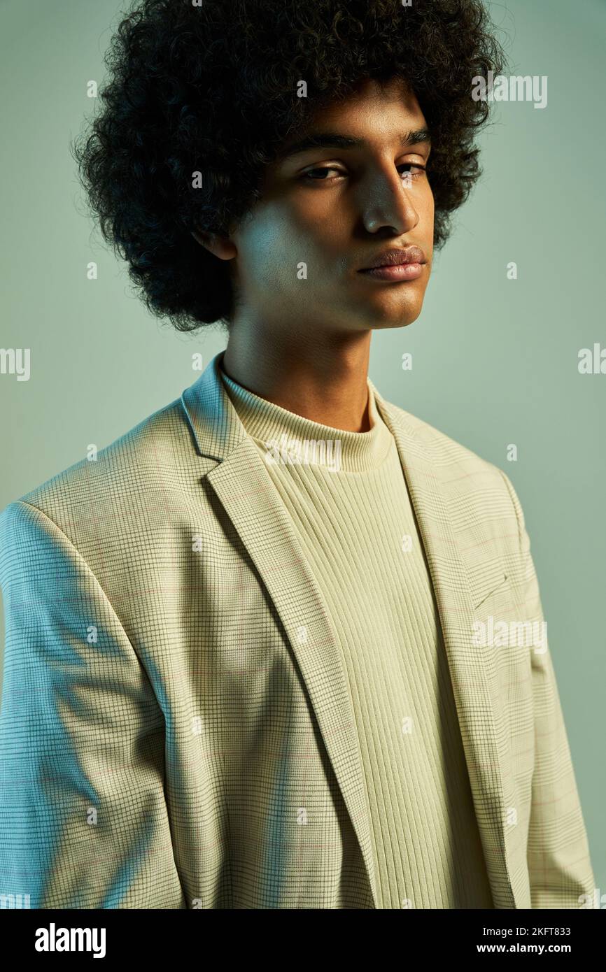 Side view young Hispanic male model in stylish suit with curly hair ...