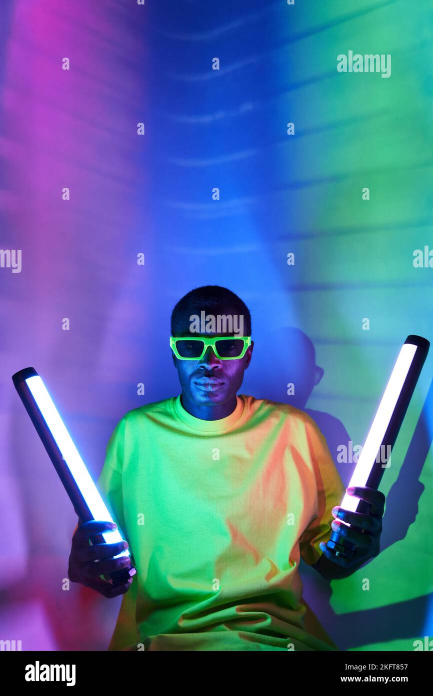 Black male in sunglasses and trendy clothes holding fluorescent lamps ...