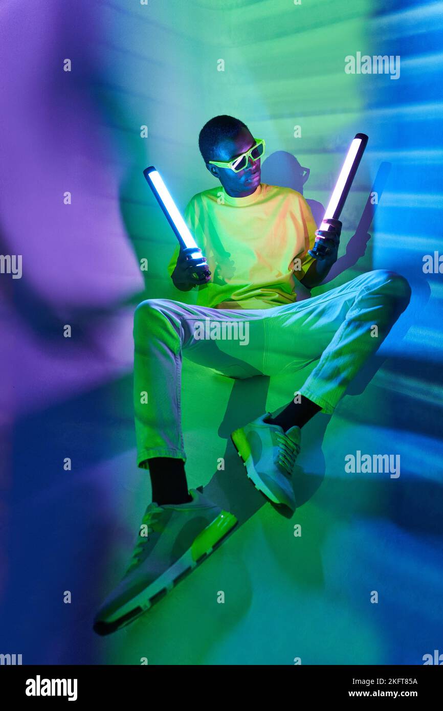 Full body male in sunglasses and trendy clothes holding fluorescent ...