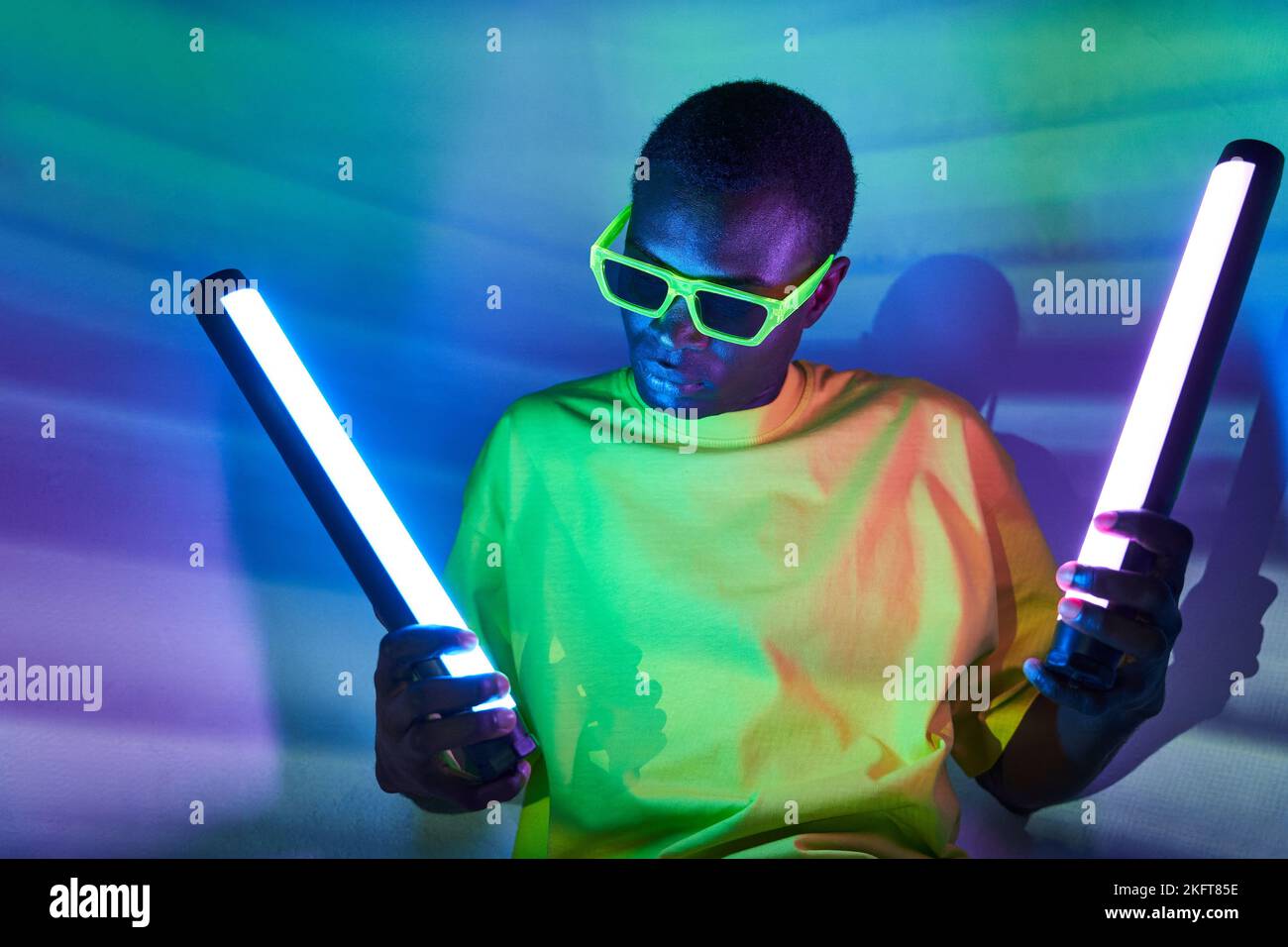 Black male in sunglasses and trendy clothes holding fluorescent lamps ...