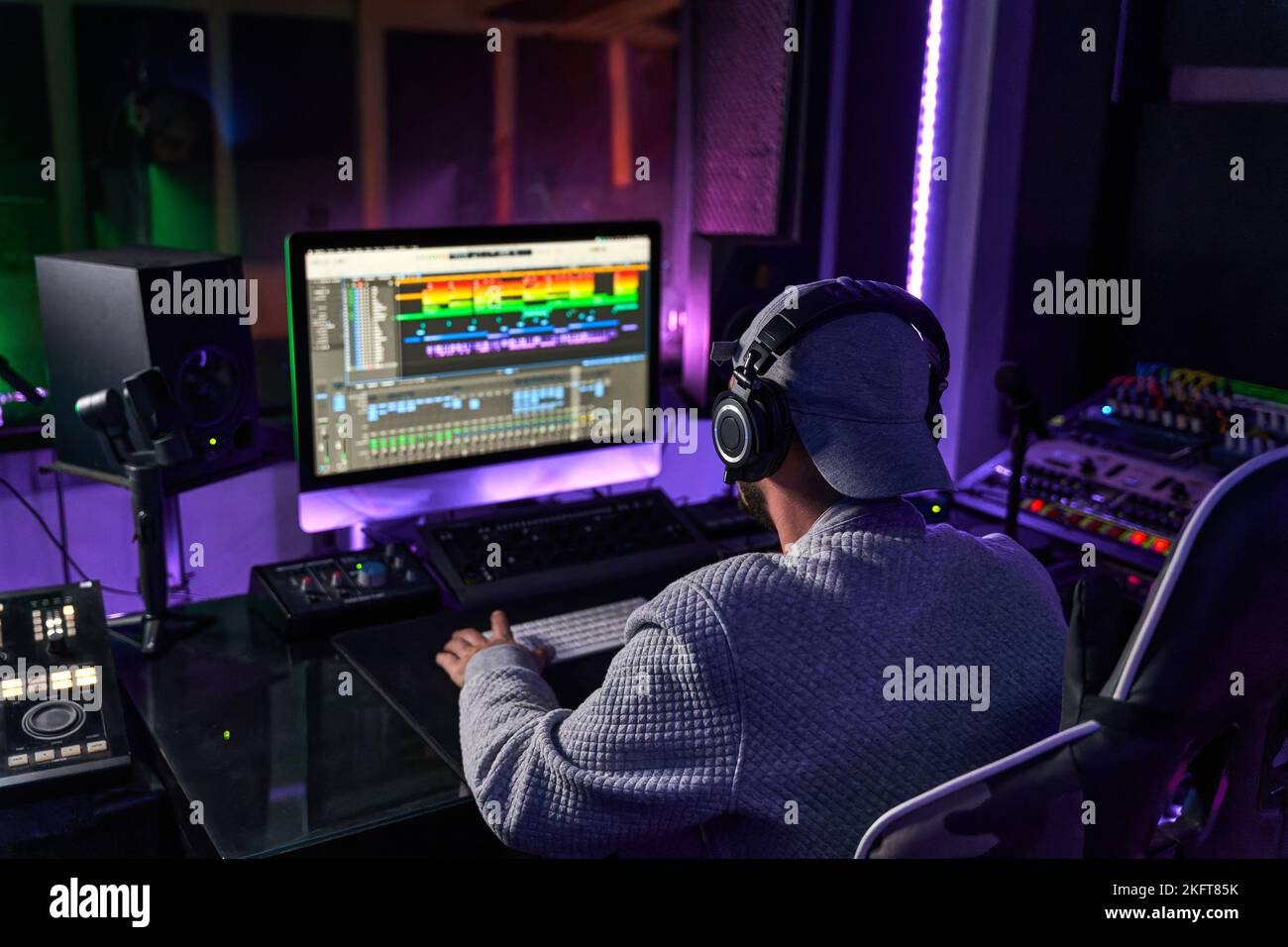 Back view of anonymous male audio engineer using computer while ...