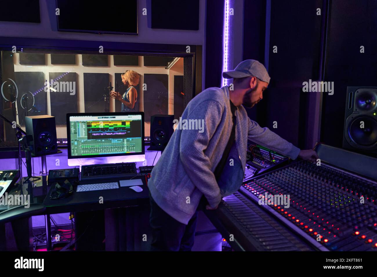 Side view of focused male recording engineer standing at workplace with ...