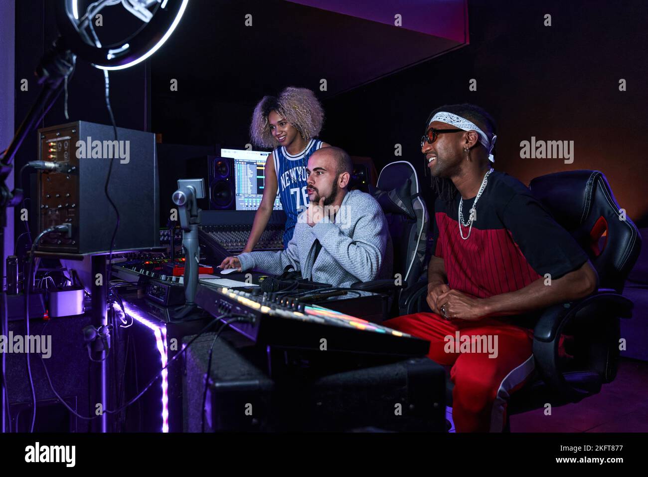 Positive multiethnic people gathering in modern recording studio while ...