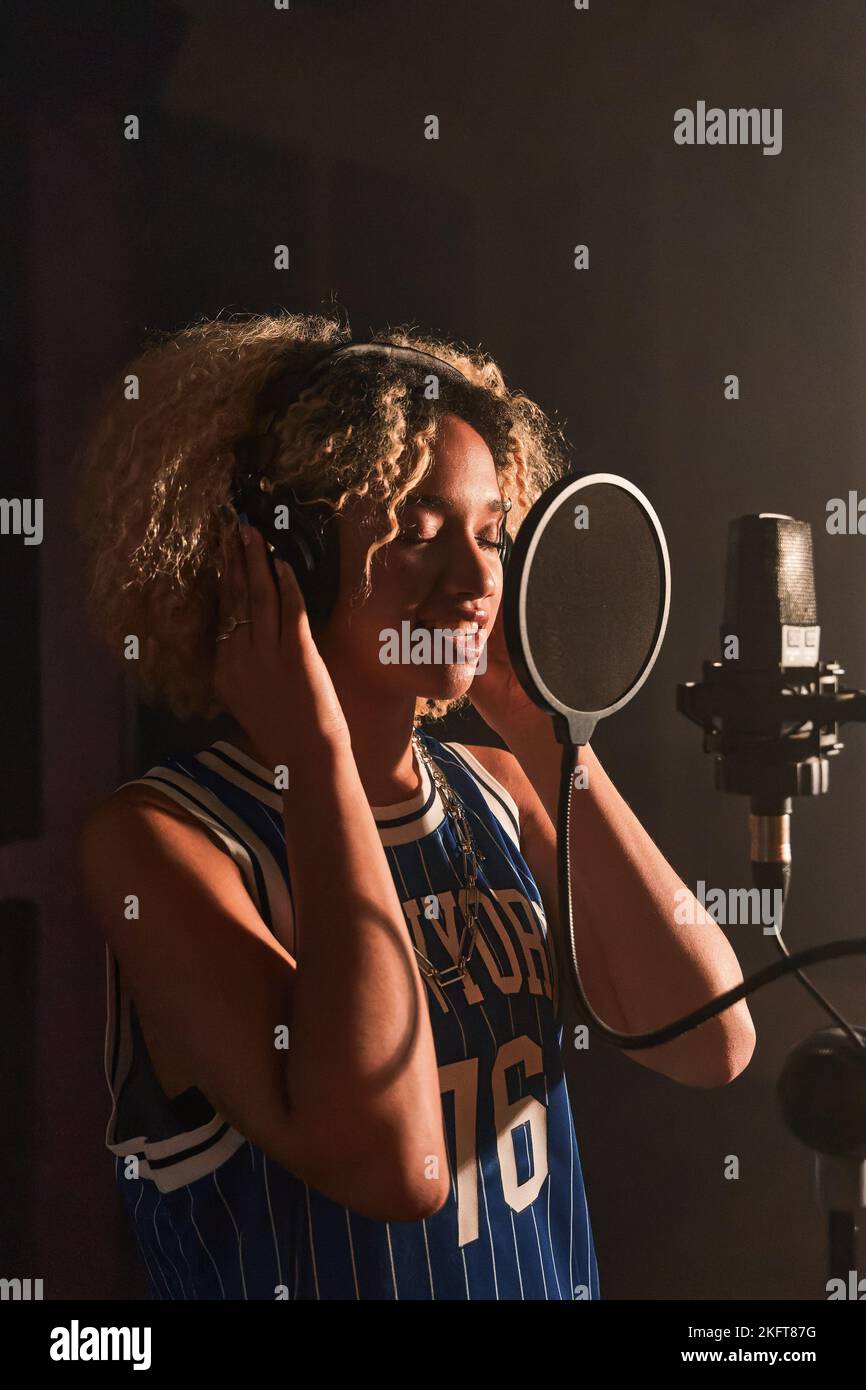 Side view of focused young female singer with Afro hairstyle standing ...
