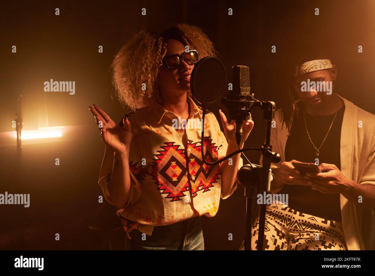 Side view of young female singer with Afro hairstyle standing against ...