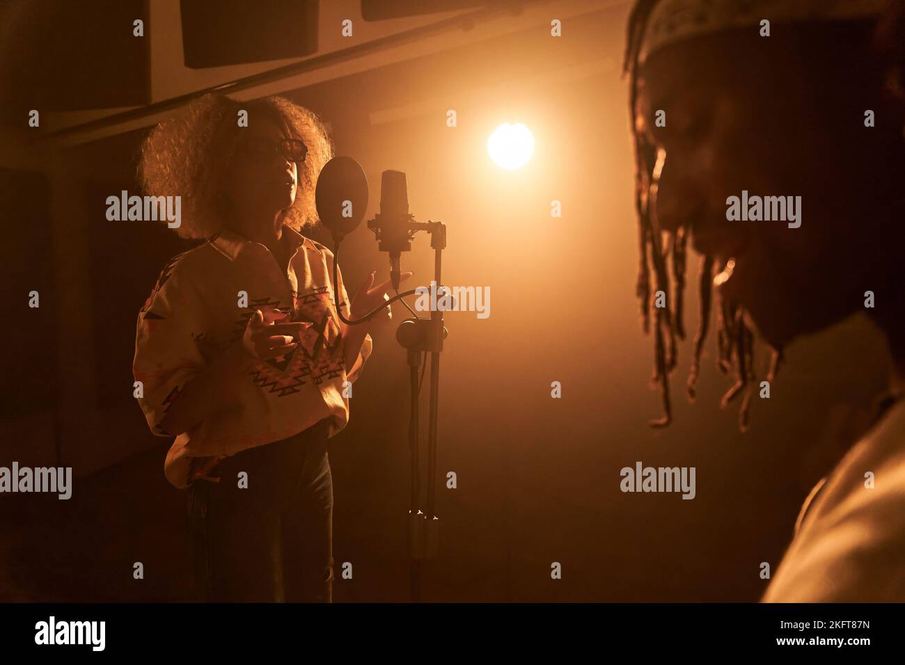 Young African American woman singer standing in studio recording song ...
