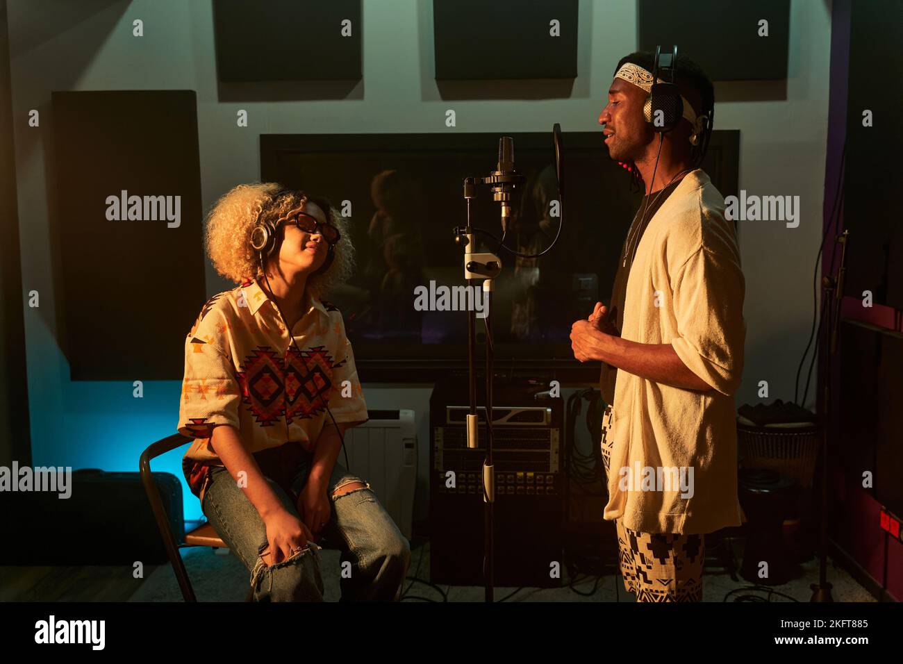 Young African American male singer standing in studio recording song ...