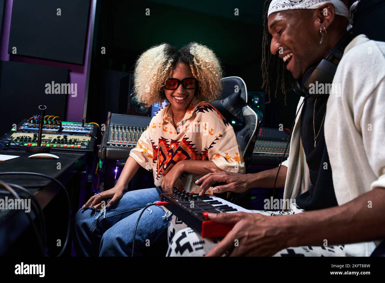 Positive crop African American man playing music on synthesizer while ...