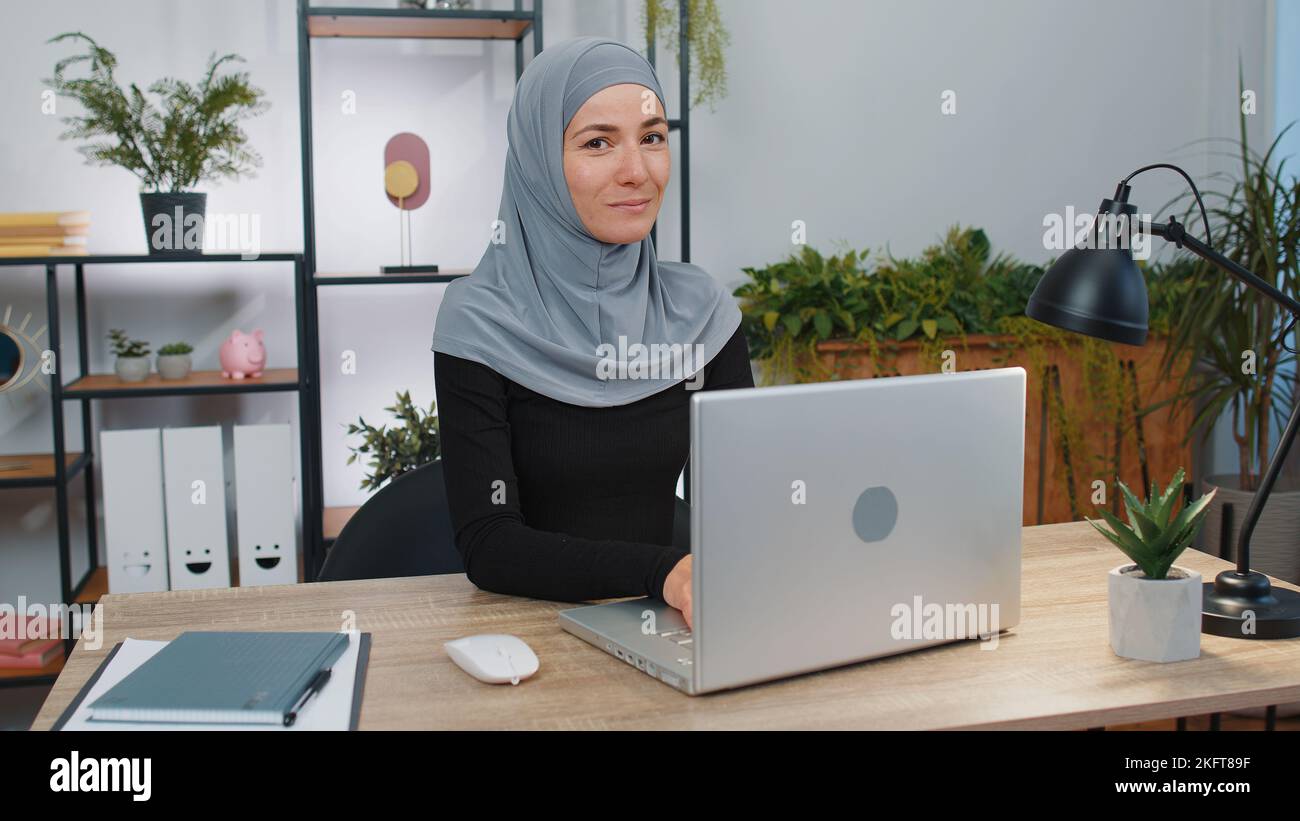 Young muslim business woman freelancer in hijab headscarf opens laptop ...