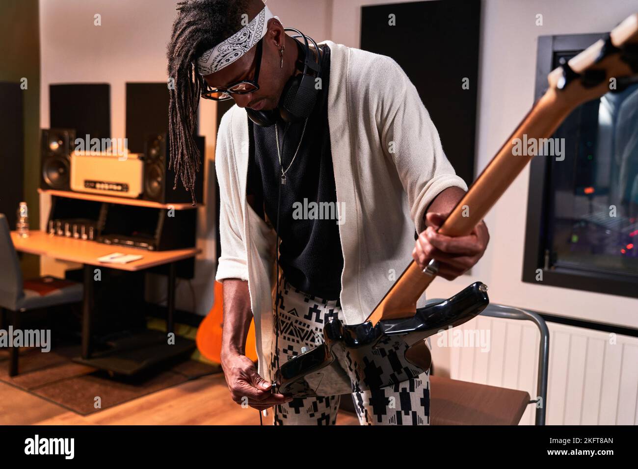 African American male musician with dreadlocks inserting cable into ...