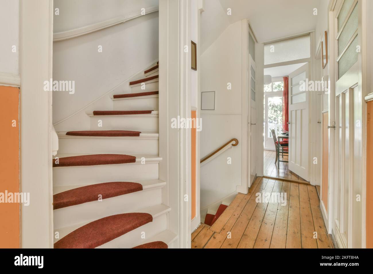 White interior of narrow hall and red staircase in contemporary cottage ...