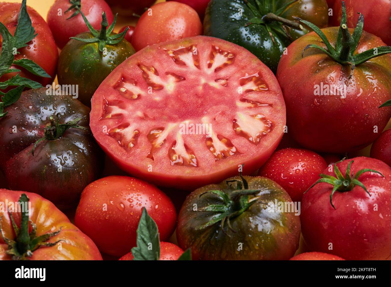 High angle of sliced tomato among ripe whole red tomatoes with water drops Stock Photo - Alamy