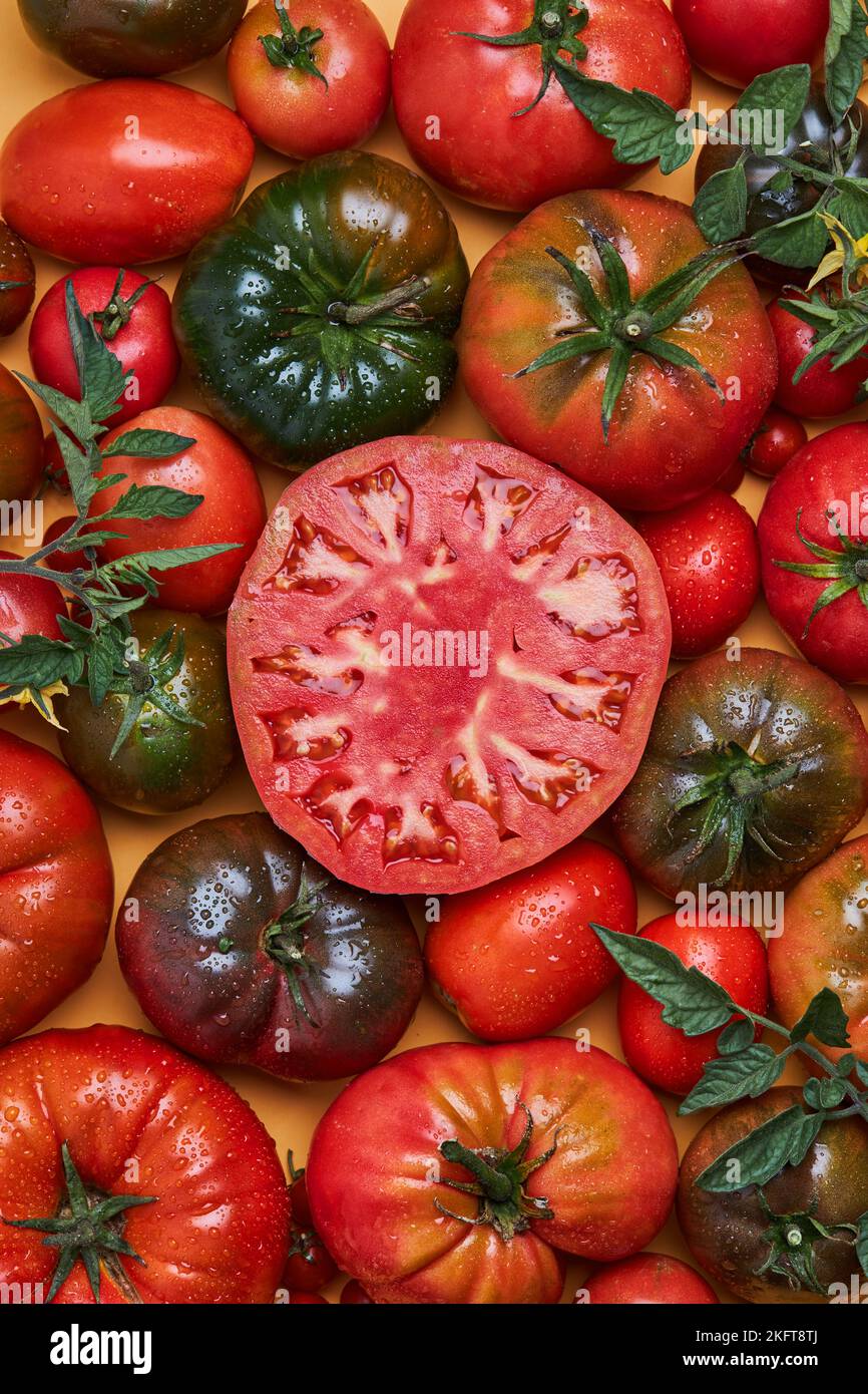 High angle of sliced tomato among ripe whole red tomatoes with water drops Stock Photo - Alamy