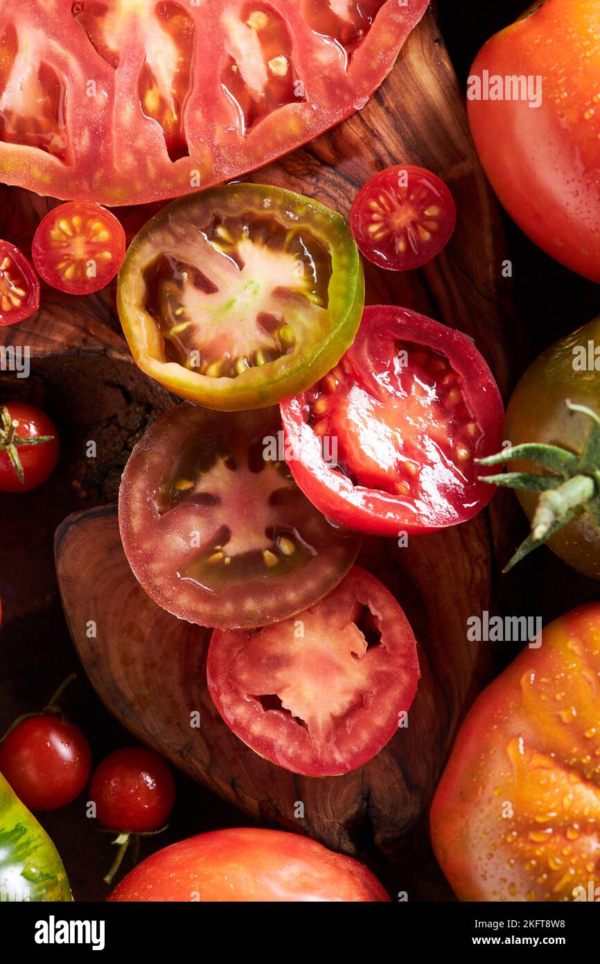 High angle of sliced tomato among ripe whole red tomatoes with water drops Stock Photo - Alamy