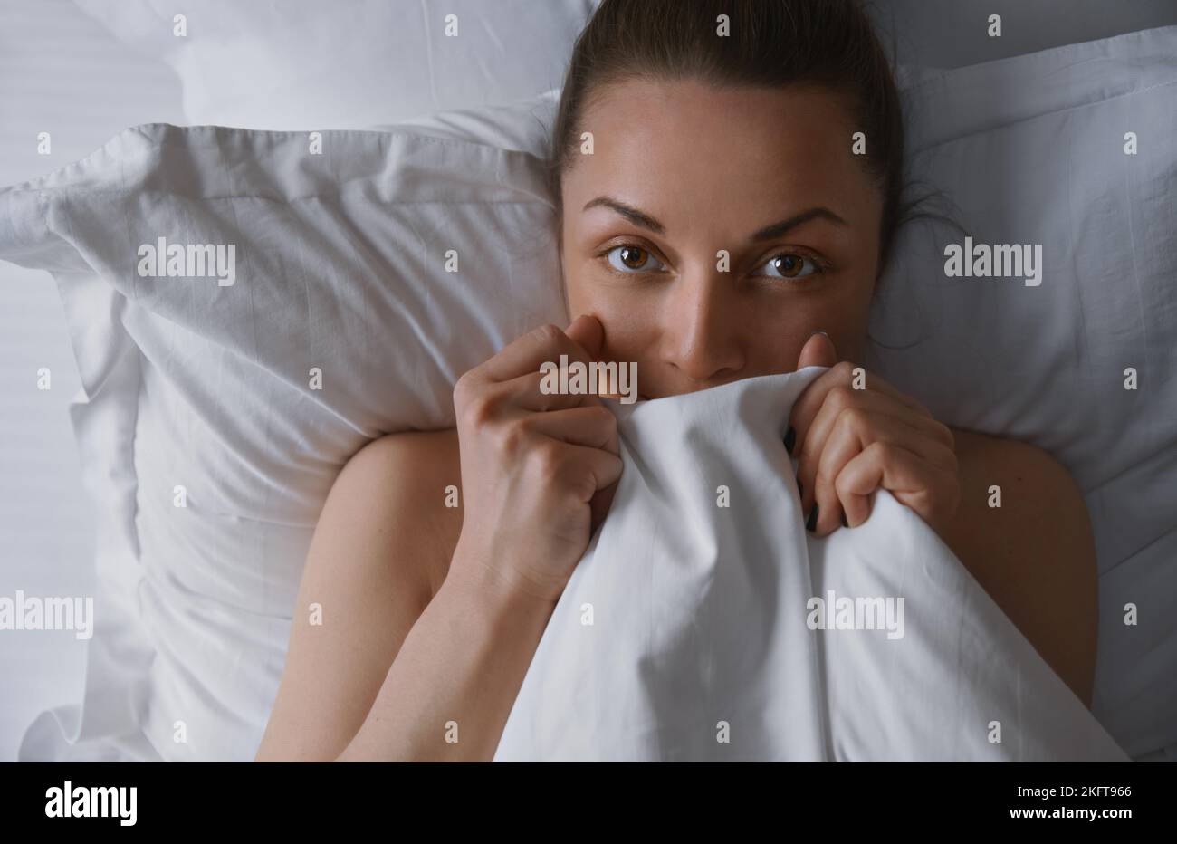 Front above Woman relaxing and peering over the top of bed sheet Stock ...