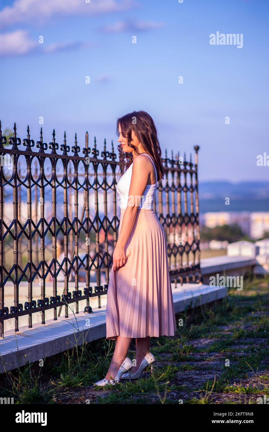 A vertical closeup shot of a woman posing sideways under the sunlight ...