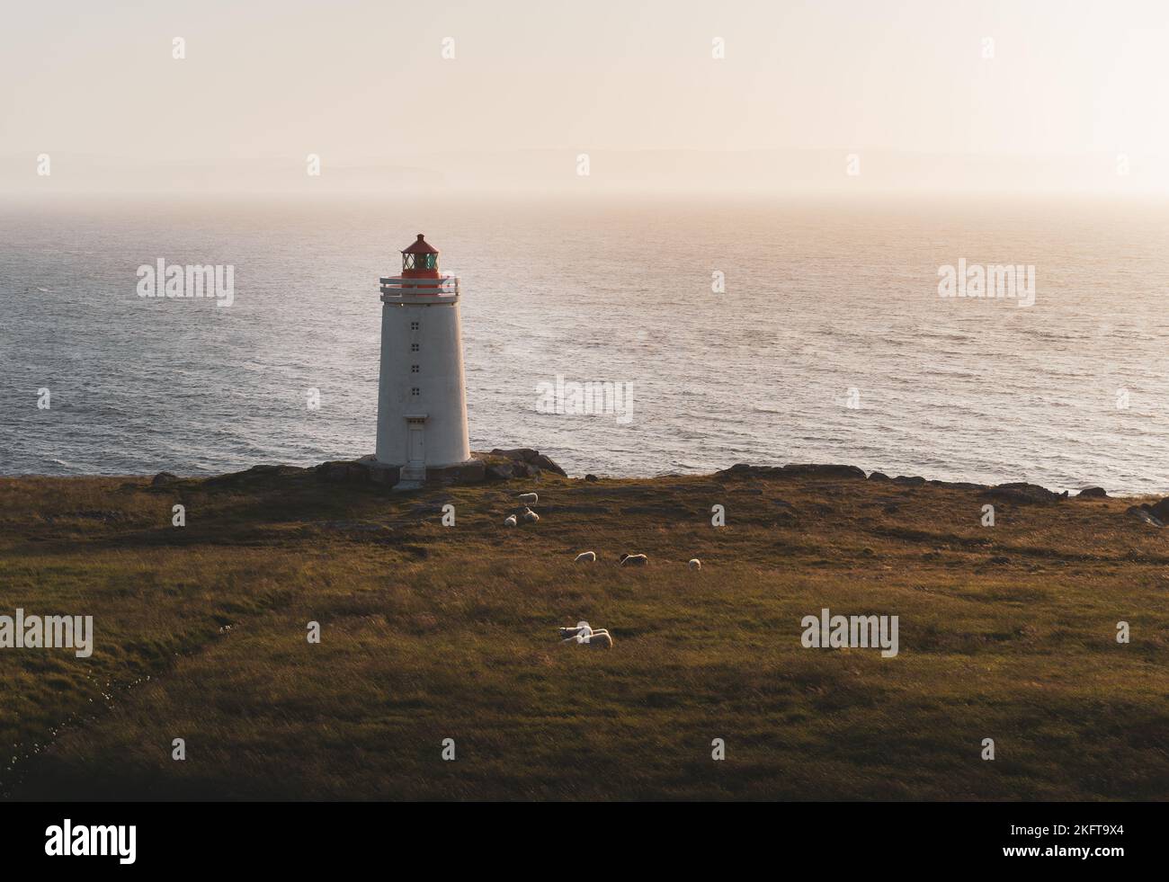 A high angle shot of a lighthouse on the edge of a cliff with the ocean ...