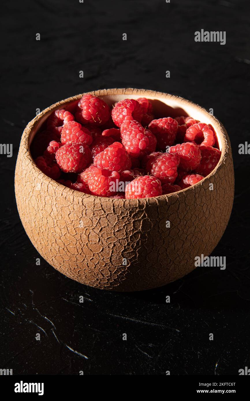 Summer food background. Red raspberry in a plate on a dark background ...