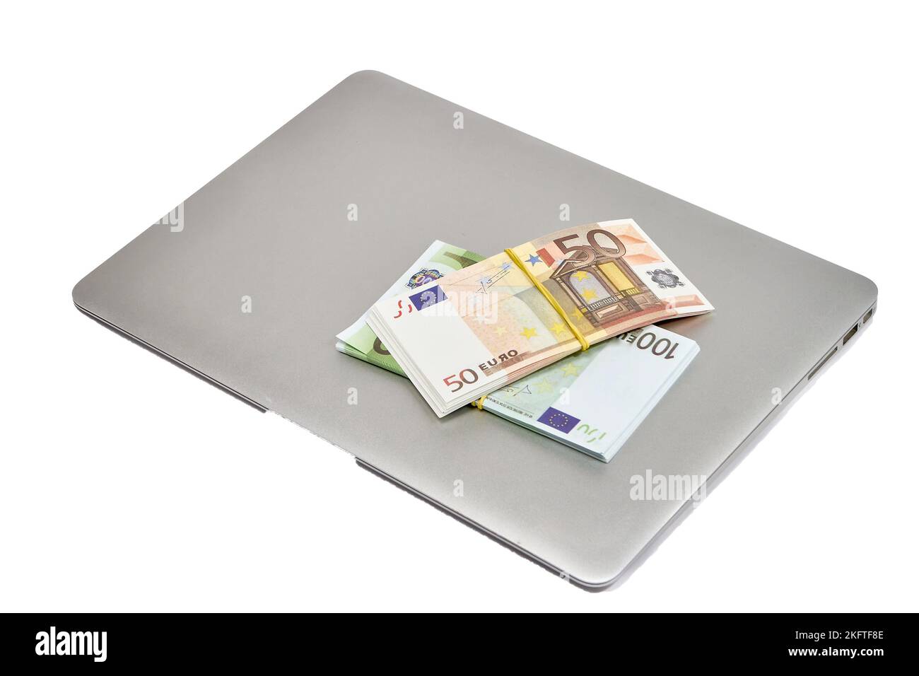 On the computer are stacks of bills of 100 and 50 euros on a white ...