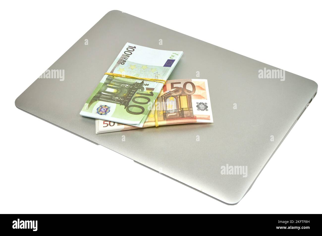 On the computer are stacks of bills of 100 and 50 euros on a white ...