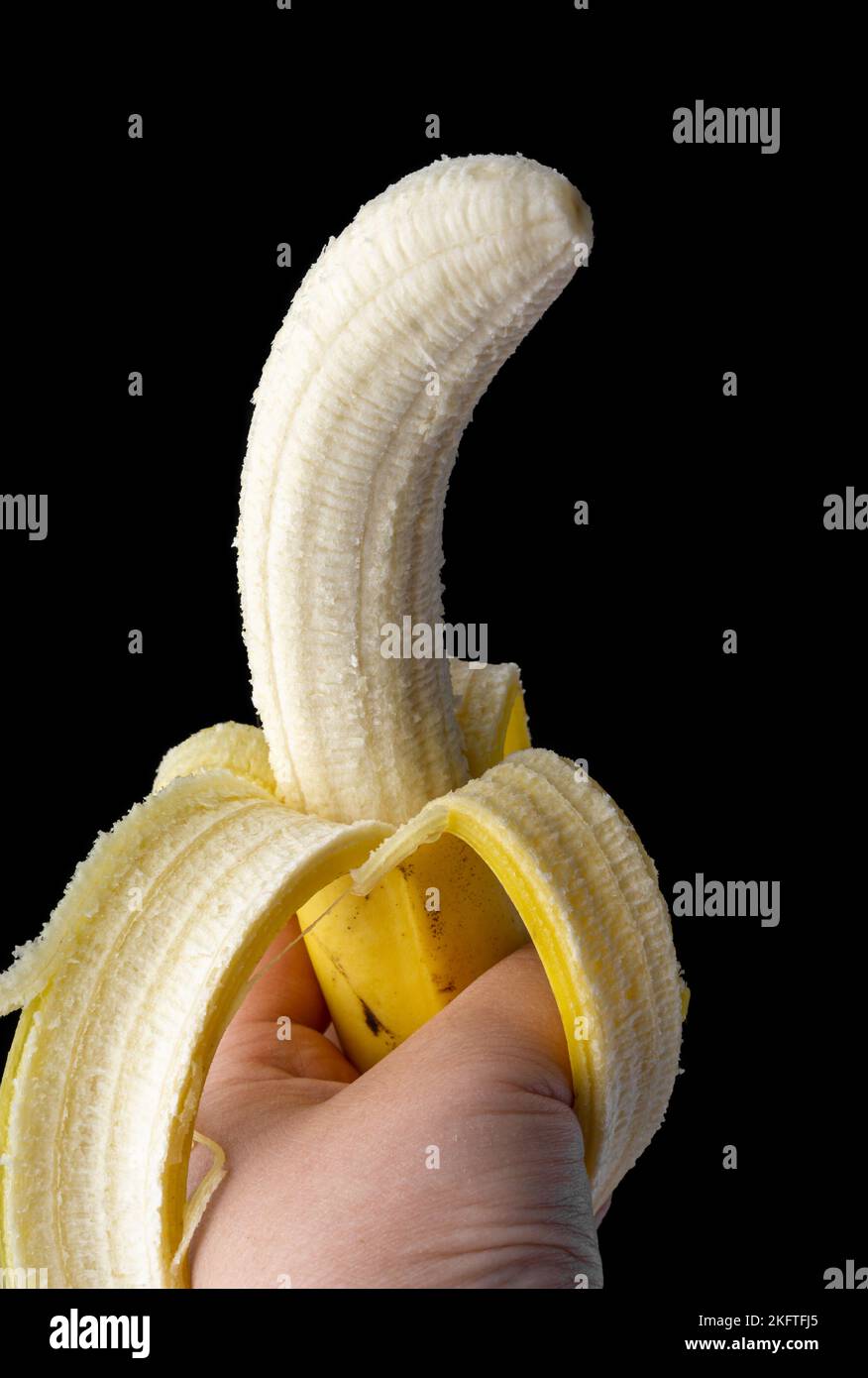 Asian woman's hand holding a fresh, yellow banana. Isolated on black ...