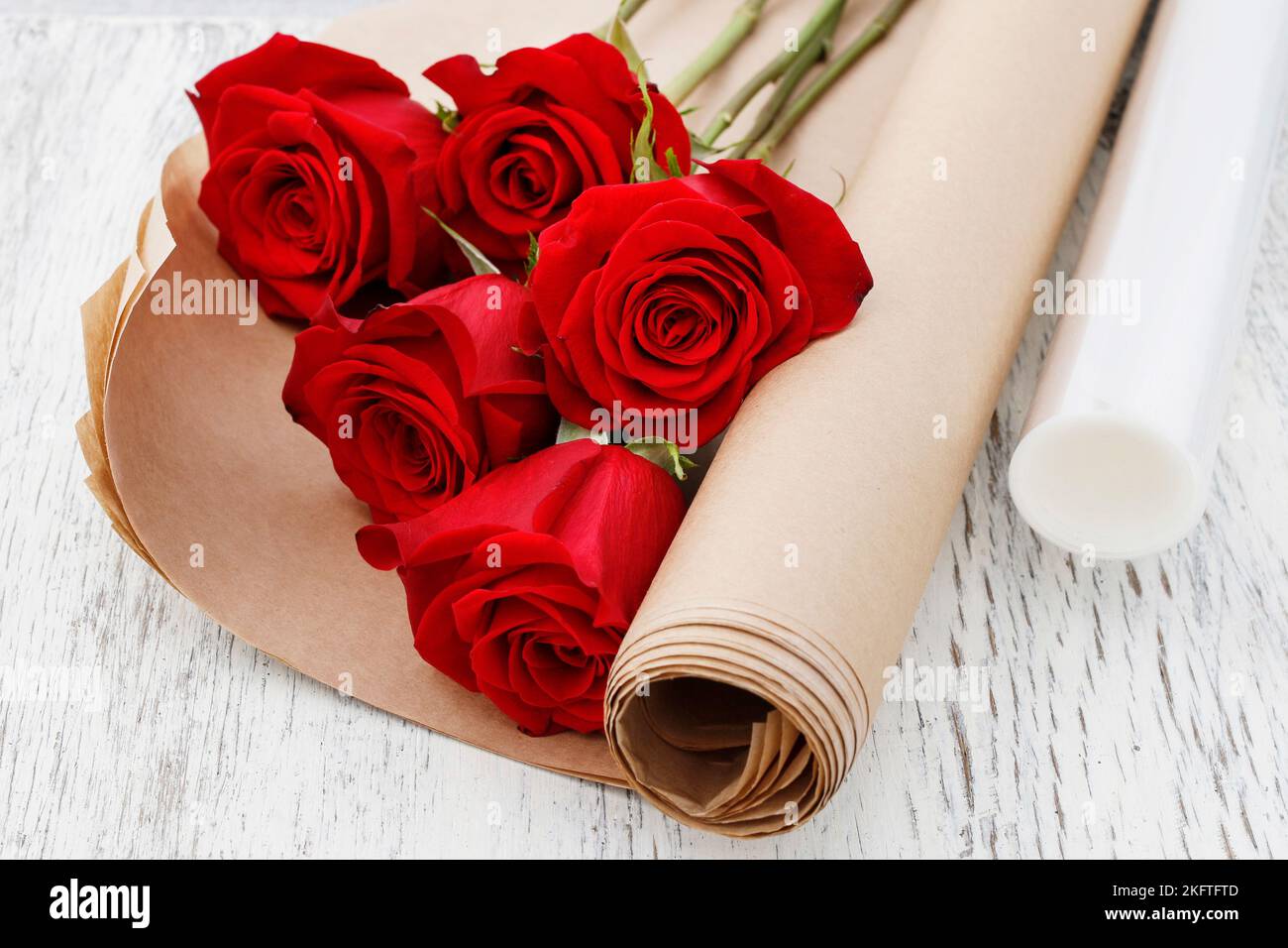 Paper or plastic stretch film as wrapping for red rose flowers. copy ...