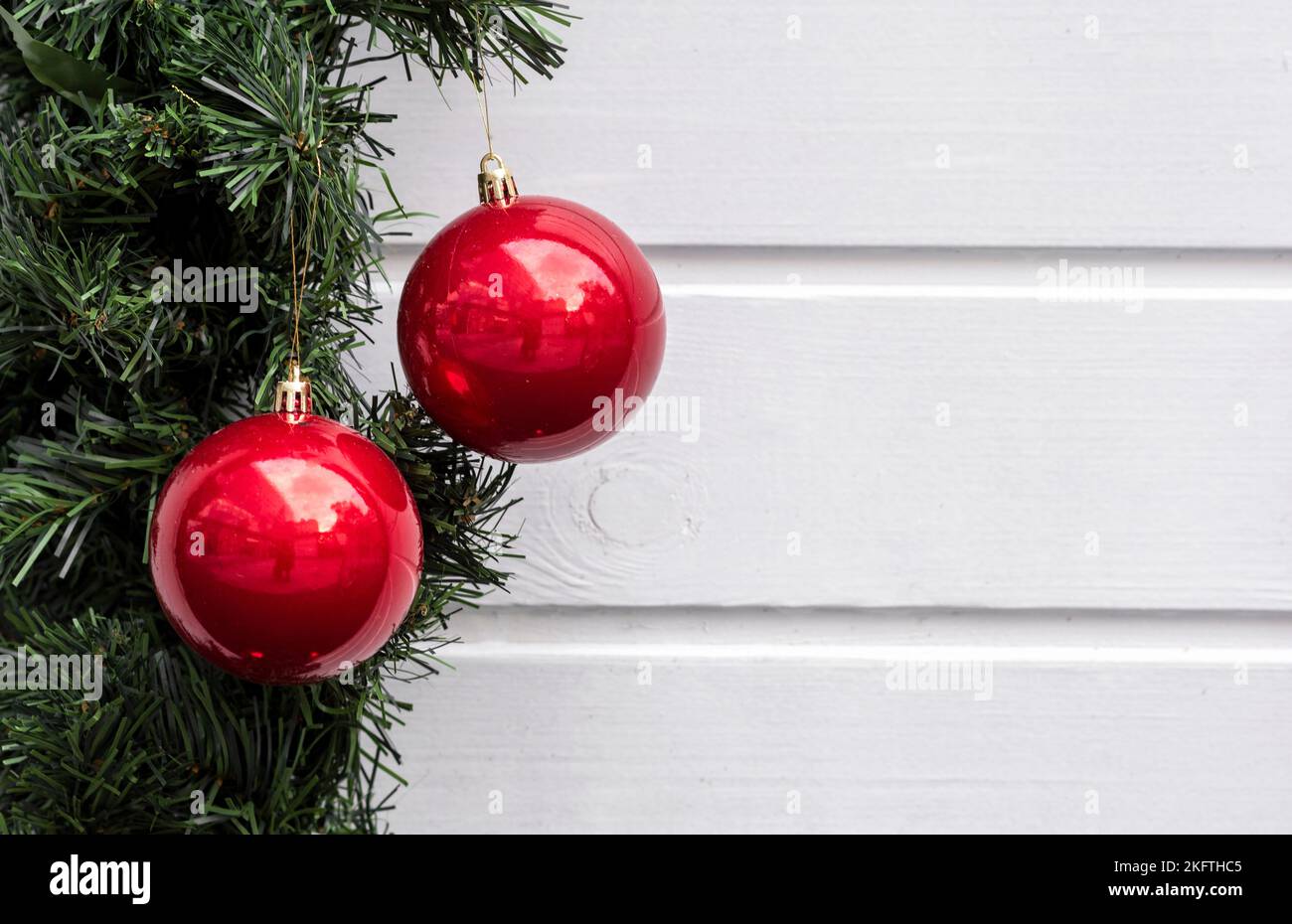 Red Christmas balls with green decor pine tree branch against white ...