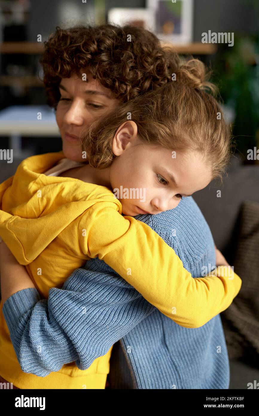 Little boy with sad expression embracing his mother after their ...