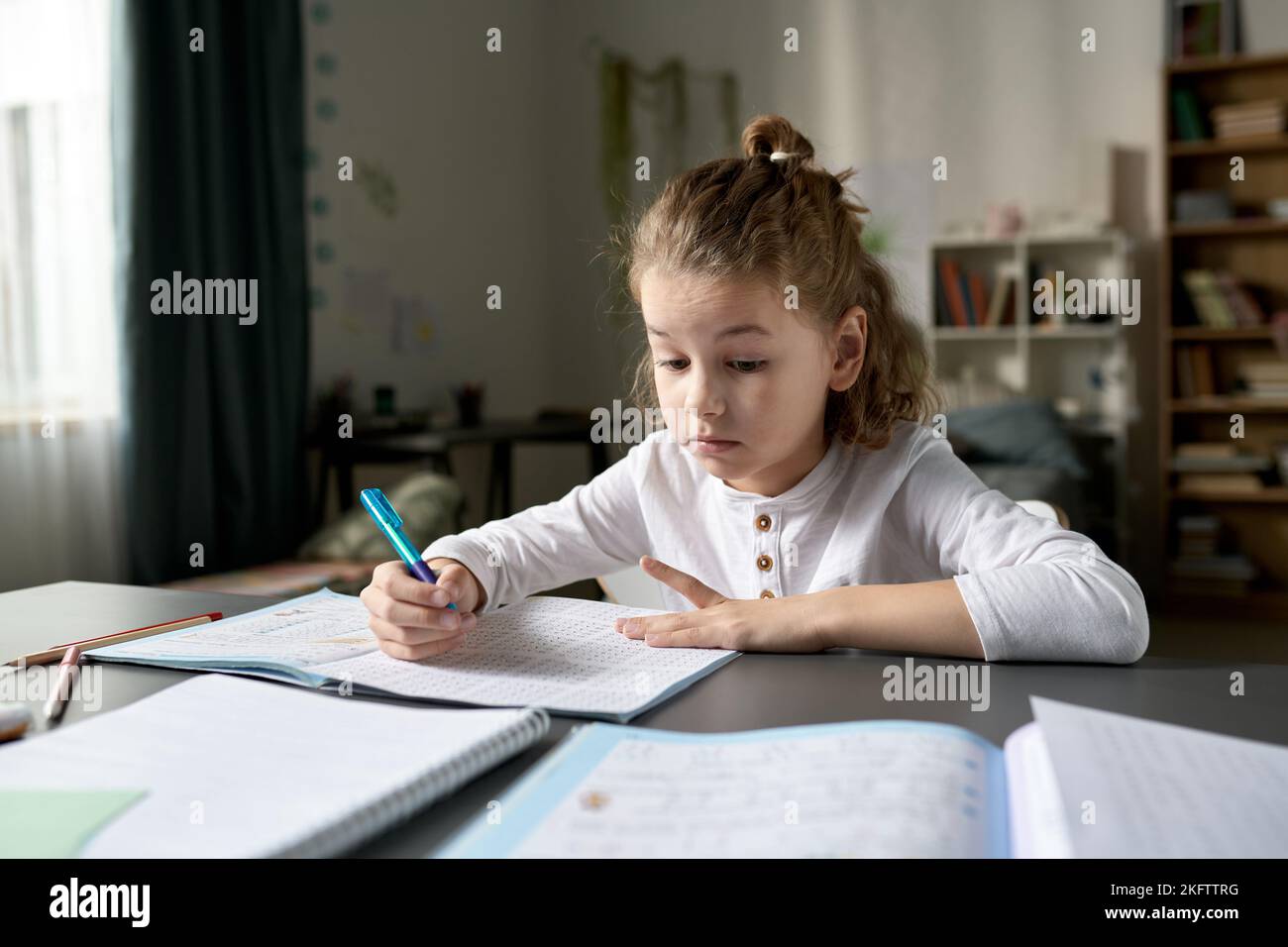 Little boy making notes in copybook at desk, he doing his homework at ...