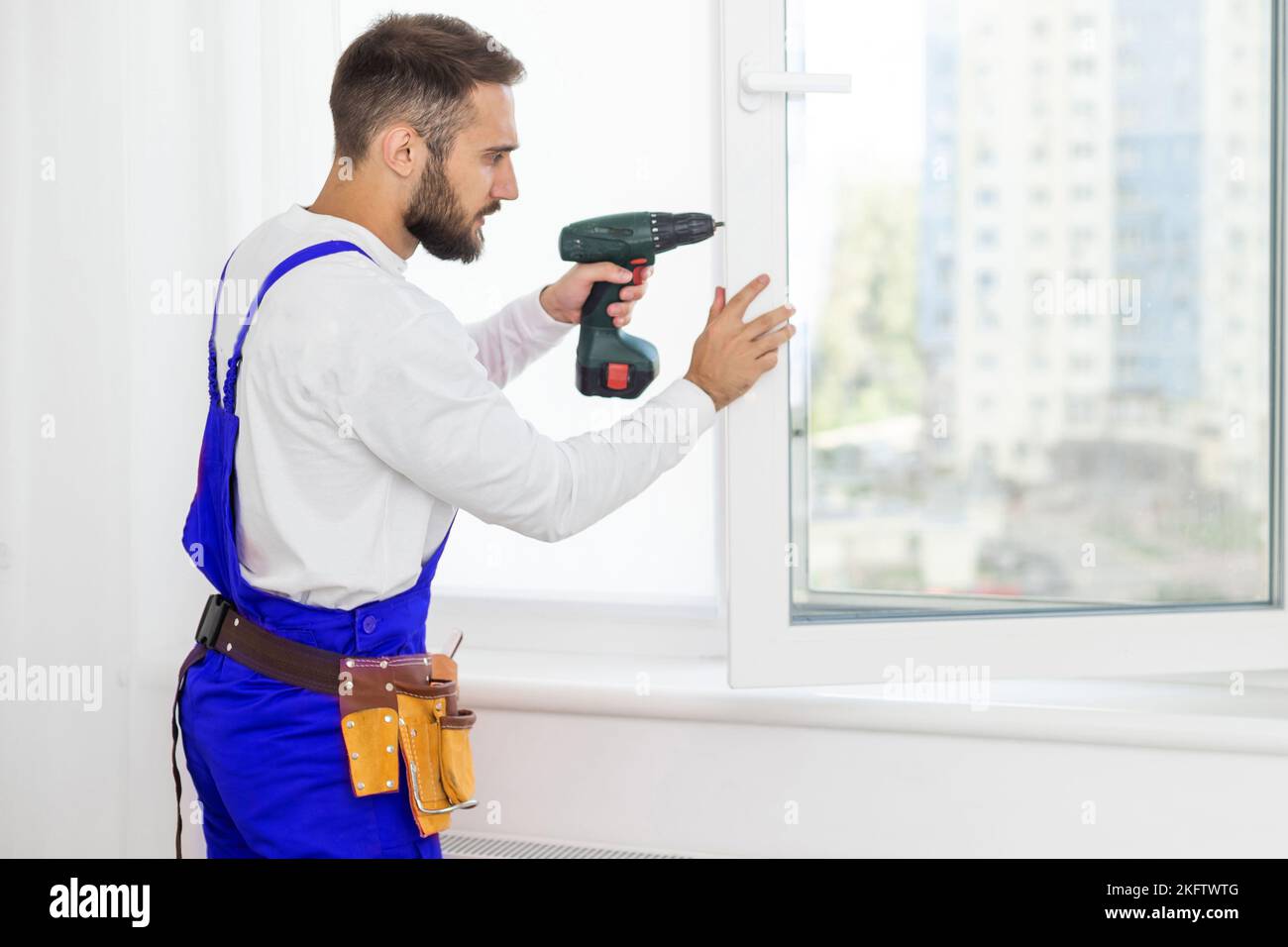 service man installing window with screwdriver Stock Photo - Alamy