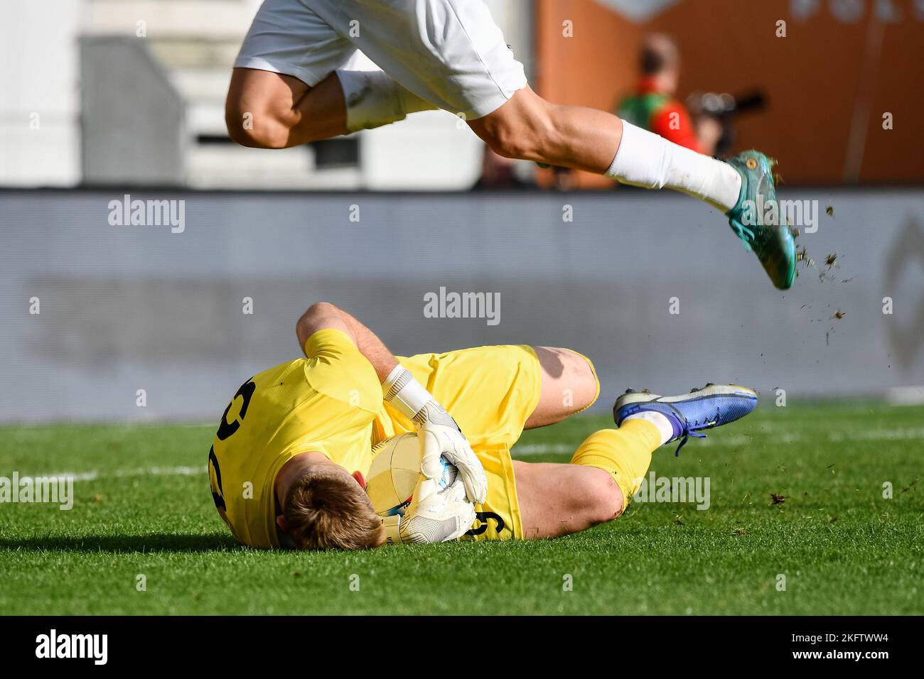 The soccer goalkeeper with the ball lies on the turf and the striker ...
