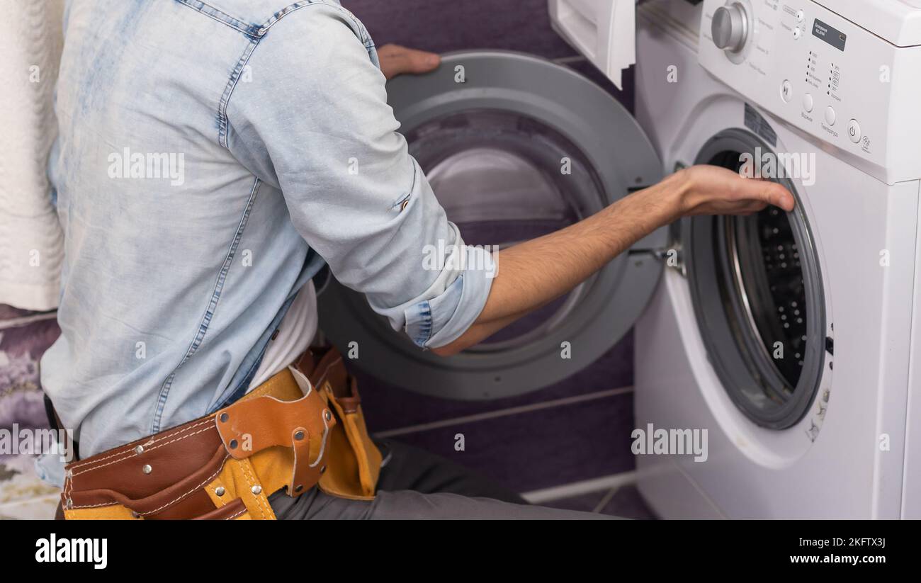 man repairs a washing machine Stock Photo - Alamy