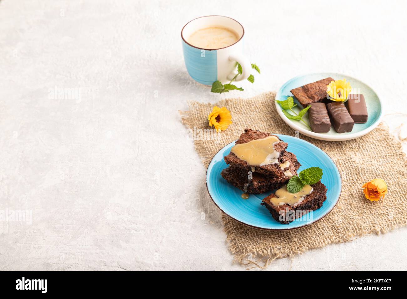 Chocolate brownie with caramel sauce with a cup of coffee on gray ...