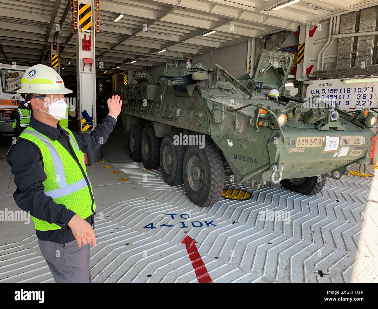 A civilian worker helps offload Stryker vehicles belonging to 2nd ...