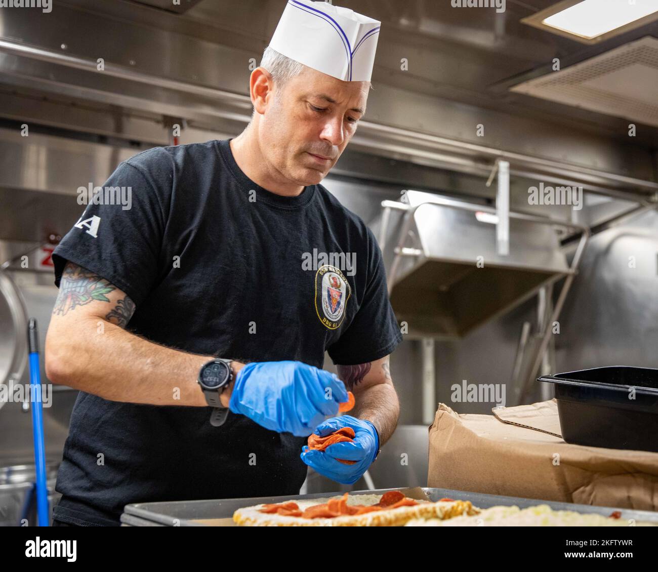 Command Master Chief David Adkins makes a pepperoni pizza for the crew ...