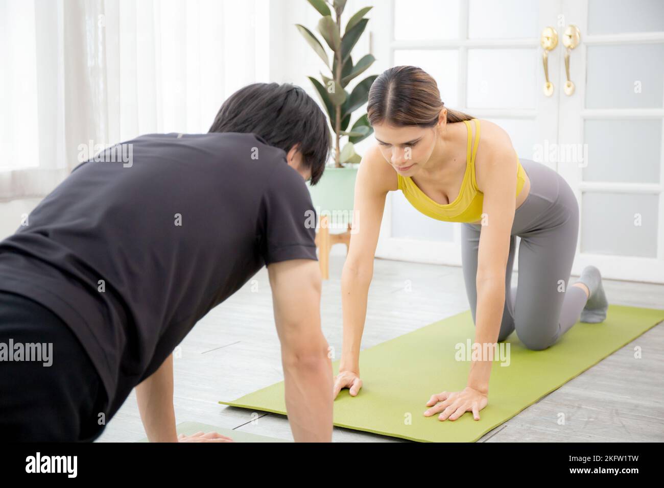 Young woman and man practicing workout with posing plank on mat while ...