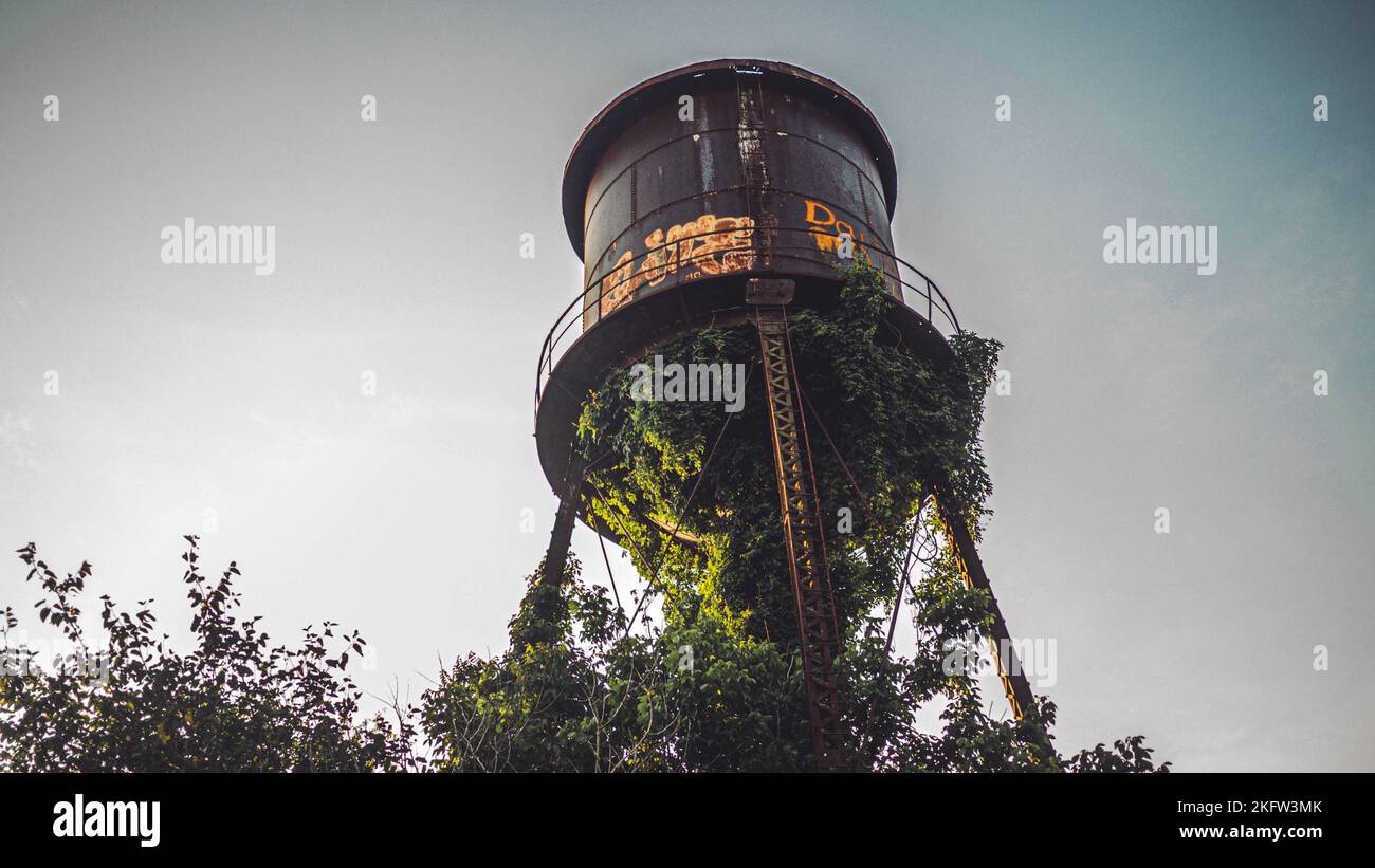 A low angle shot of an Unused and abandoned water tower with trees ...