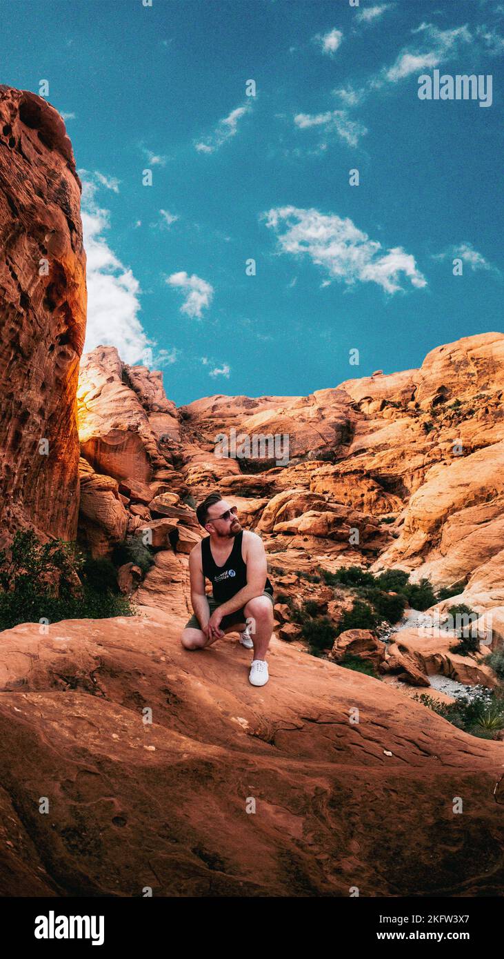 A caucasian cool male sitting on a boulder in Valley of Fire State Park ...